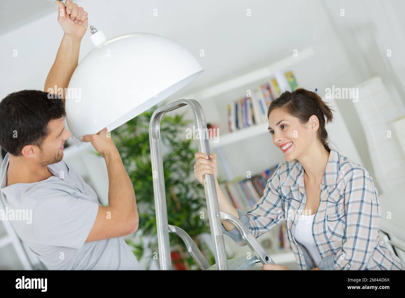 happy woman changing a light bulb on a ladder Stock Photo - Alamy
