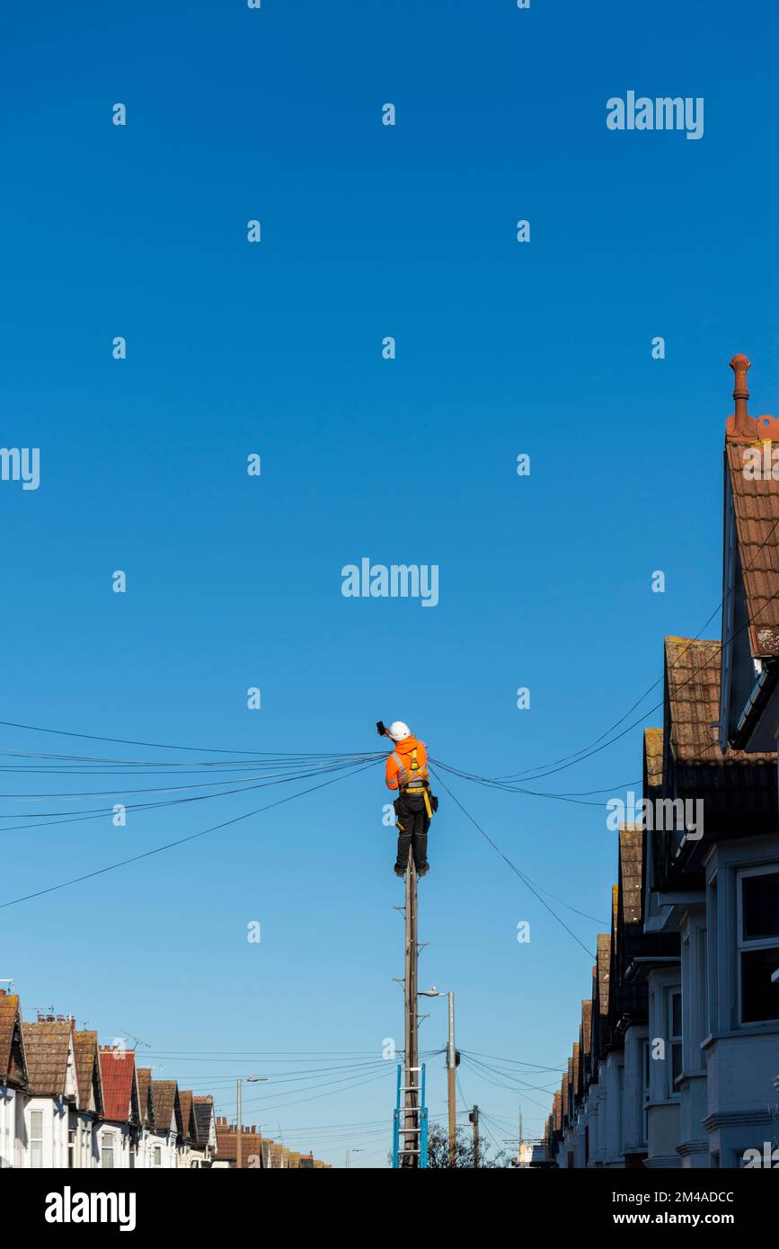 Telecommunications engineer working at the top of a telegraph pole ...