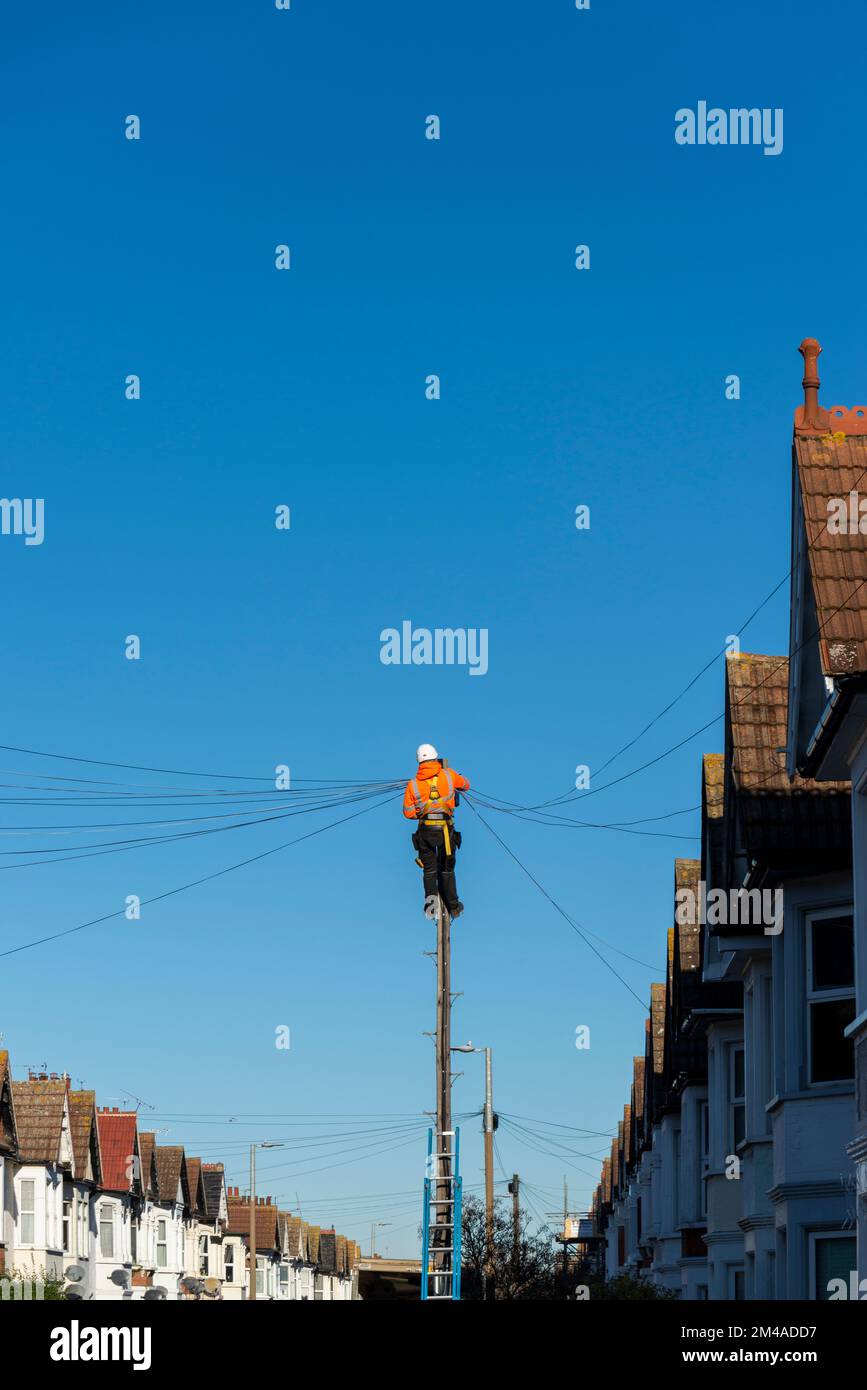 Telecommunications engineer working at the top of a telegraph pole ...