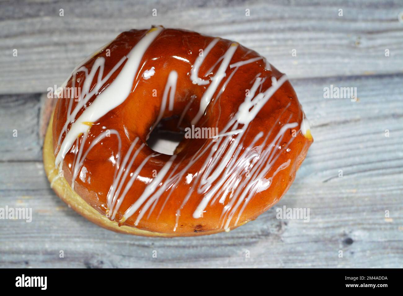 A ring donut topped with caramel and white chocolate sauce, A glazed ...