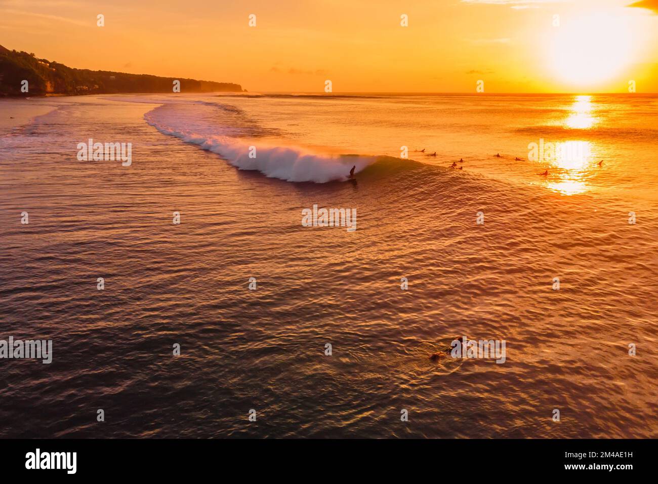 Aerial view of surfing waves with surfers at warm sunset. Perfect swell ...