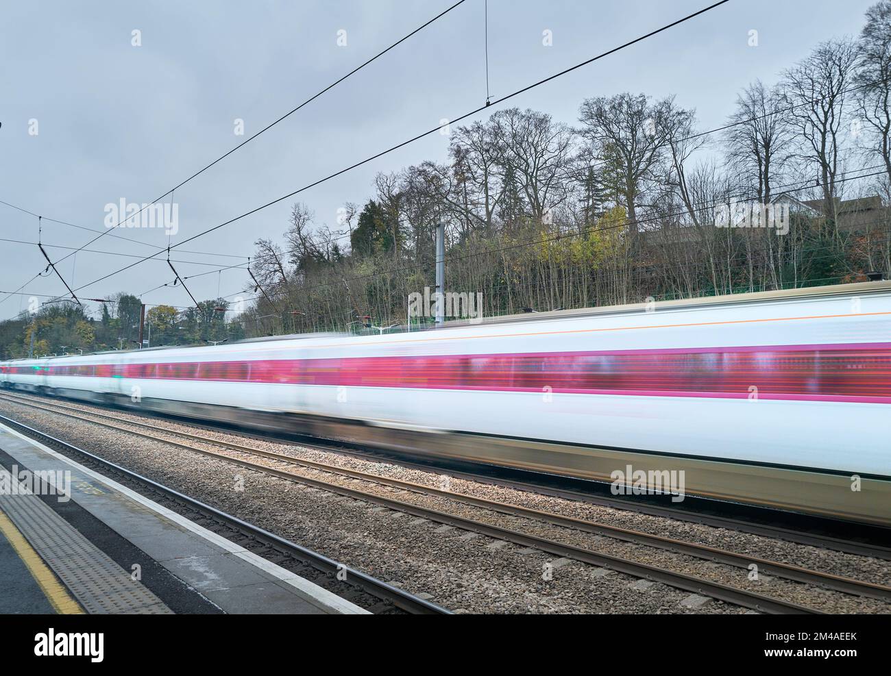 An electric train passes rapidly through the rail station at Hitchin ...