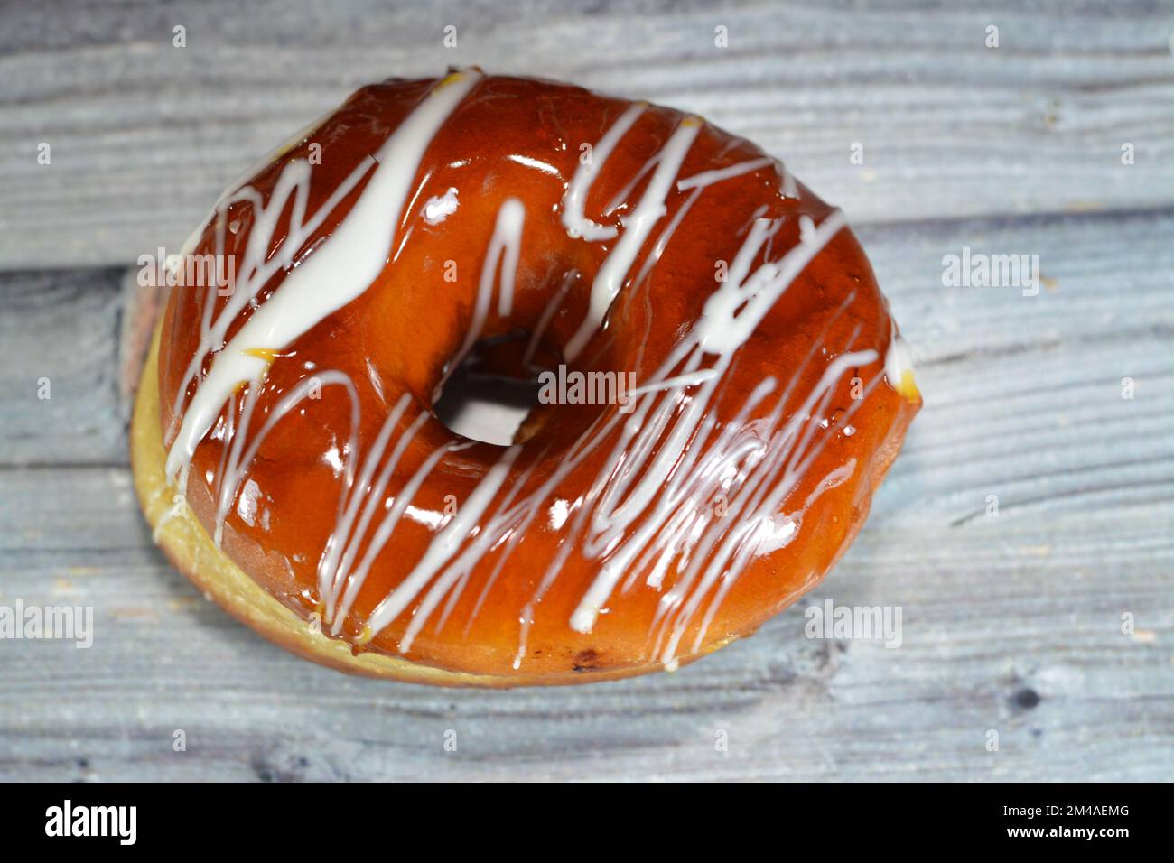 A ring donut topped with caramel and white chocolate sauce, A glazed ...
