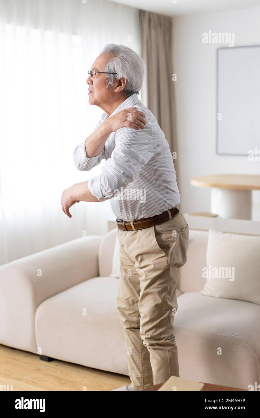 Senior Chinese man suffering from pain on shoulder Stock Photo - Alamy