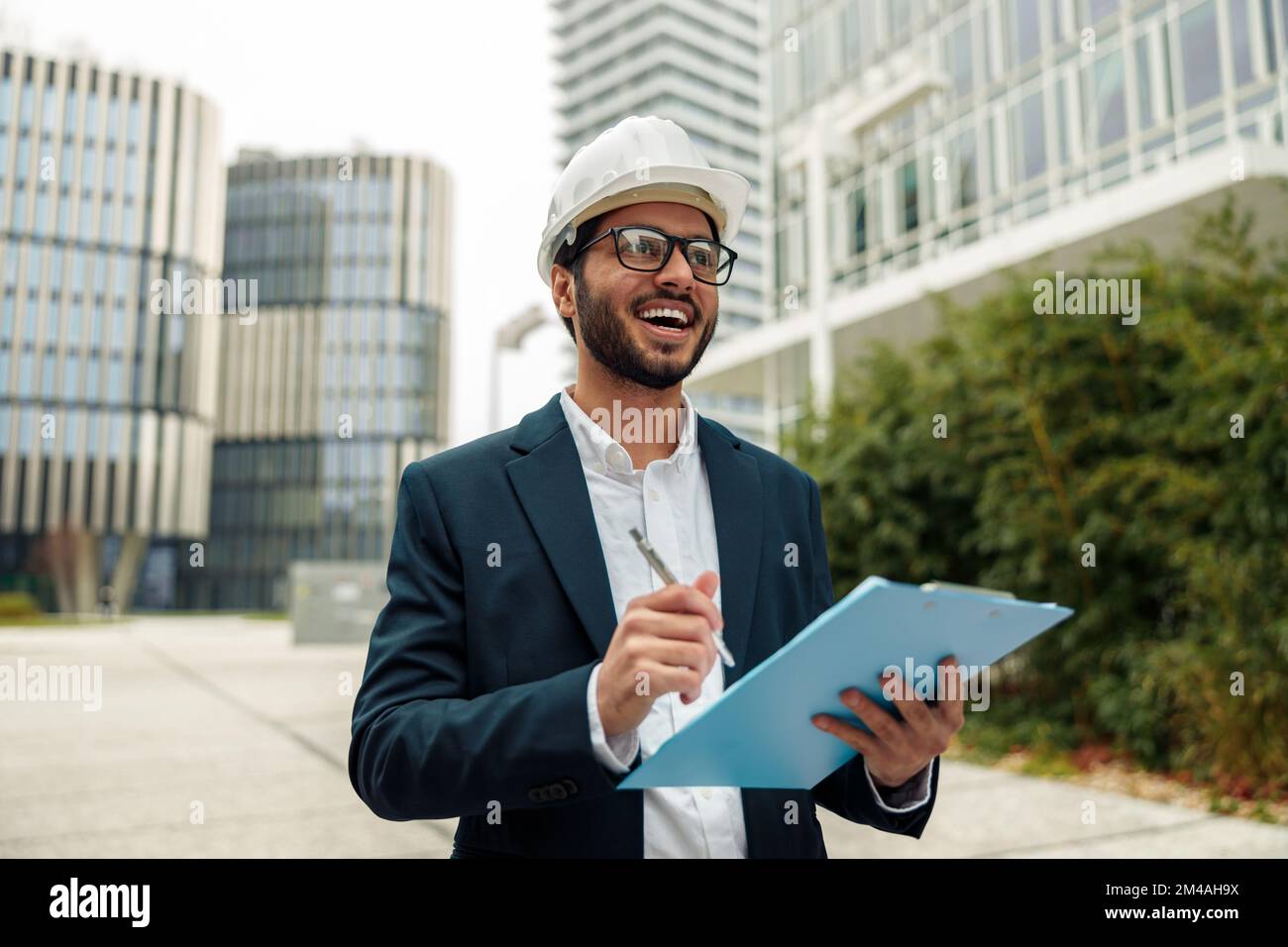Indian construction architect in suit and hardhat with paper folder in ...