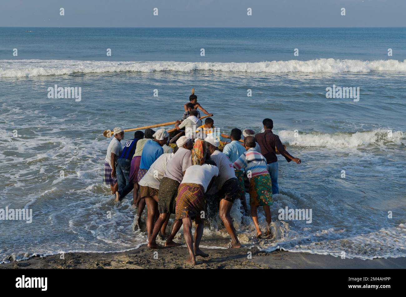 Fishermen pushing a boot into the sea at the coast around Varkala ...