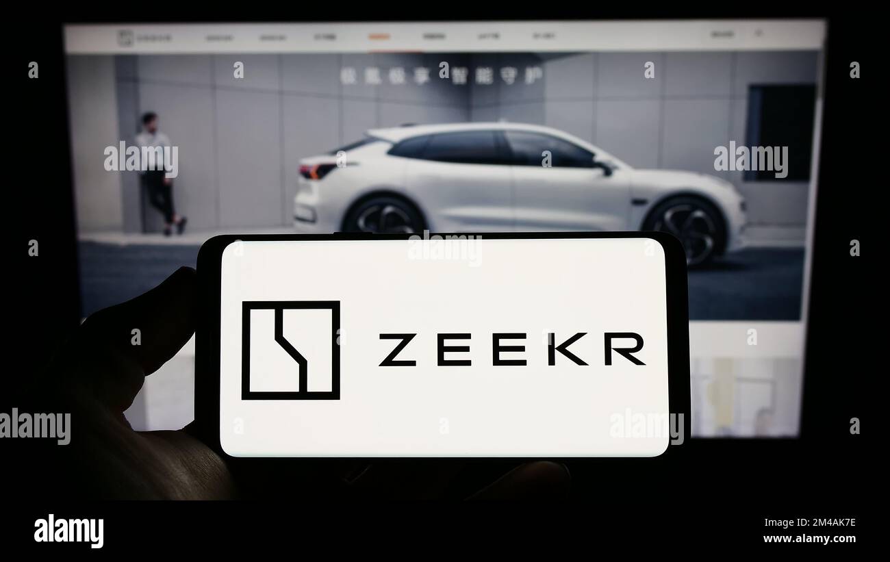 Person holding mobile phone with logo of Chinese electric automobile ...