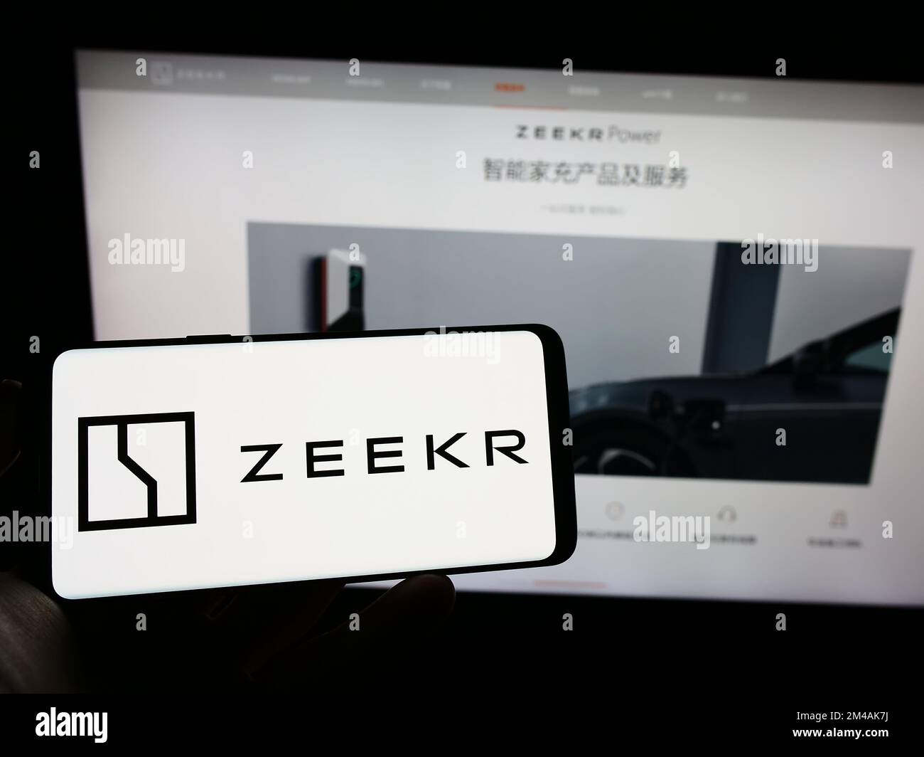 Person holding cellphone with logo of Chinese electric automobile brand ...