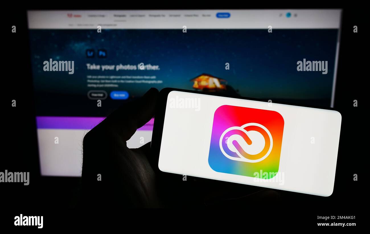 Person holding smartphone with logo of software Adobe Creative Cloud on ...