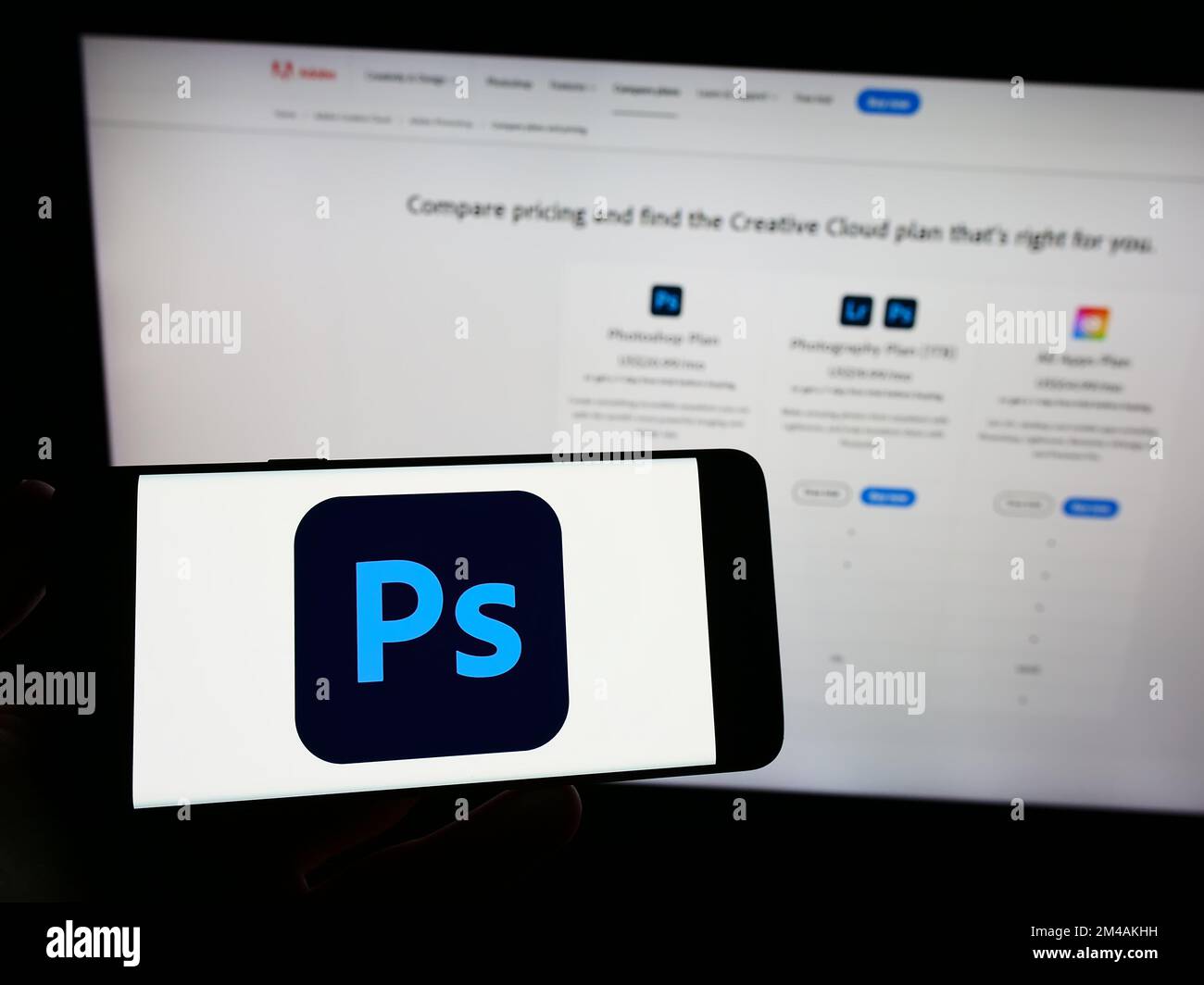 Person holding mobile phone with logo of graphics editor software Adobe ...