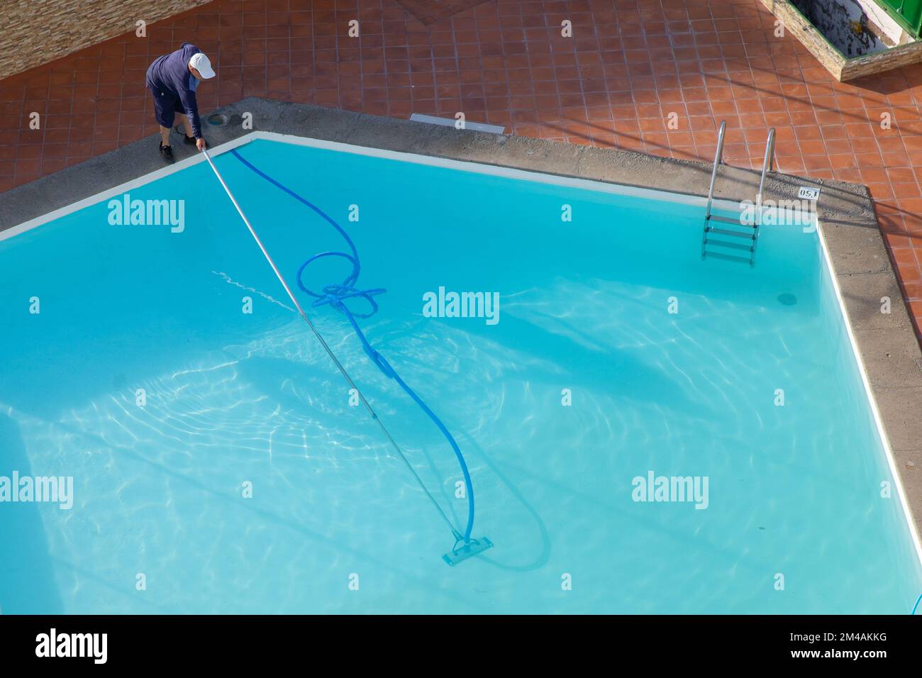 Man cleaning the swimming pool with vacuum equipment. swimming pool ...