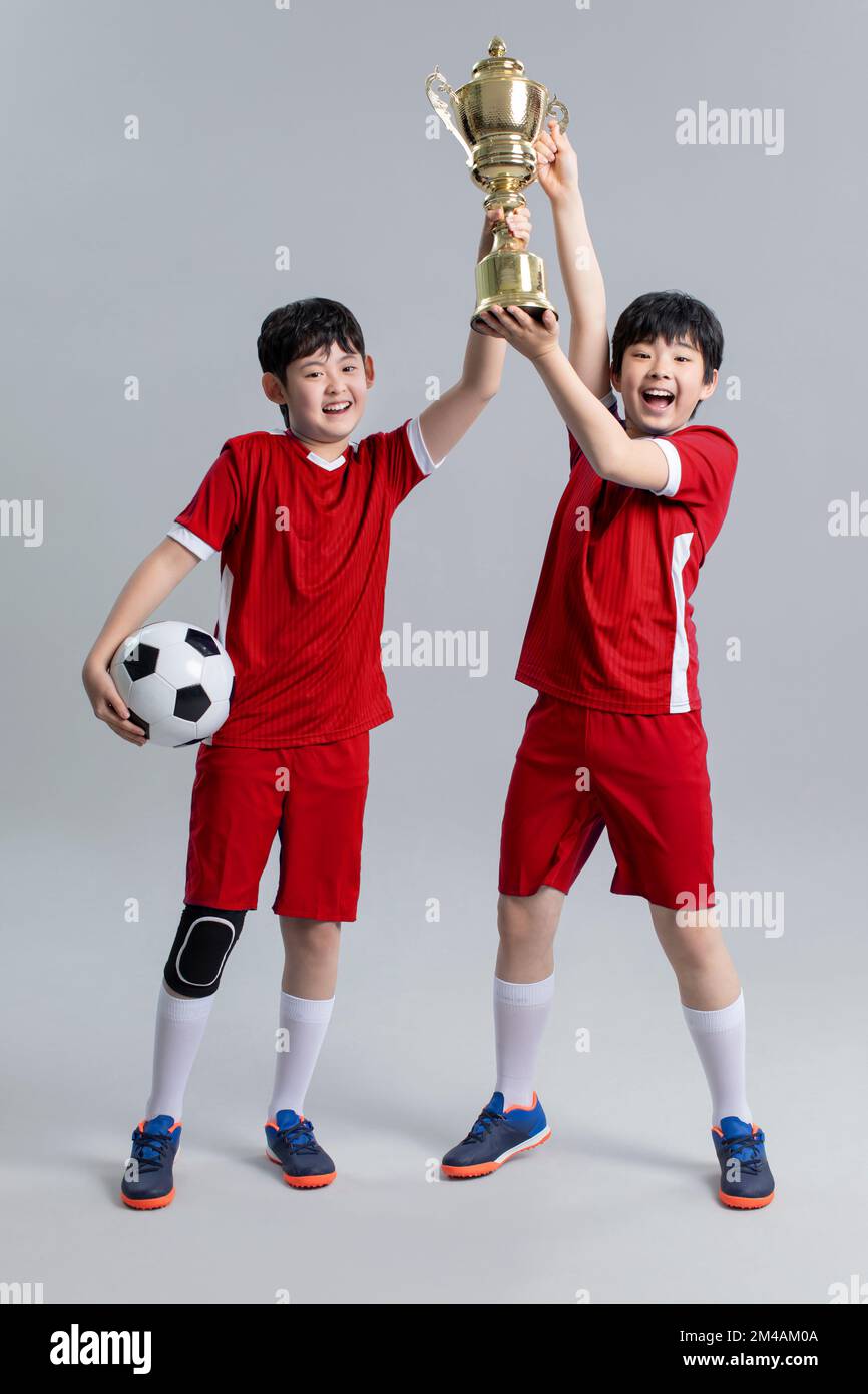 Cute Chinese soccer players showing trophy Stock Photo - Alamy