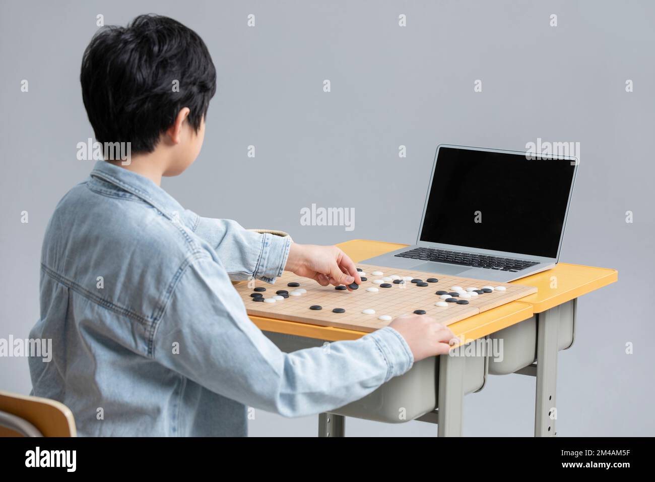 Cute Chinese boy playing the game of Go with laptop Stock Photo - Alamy