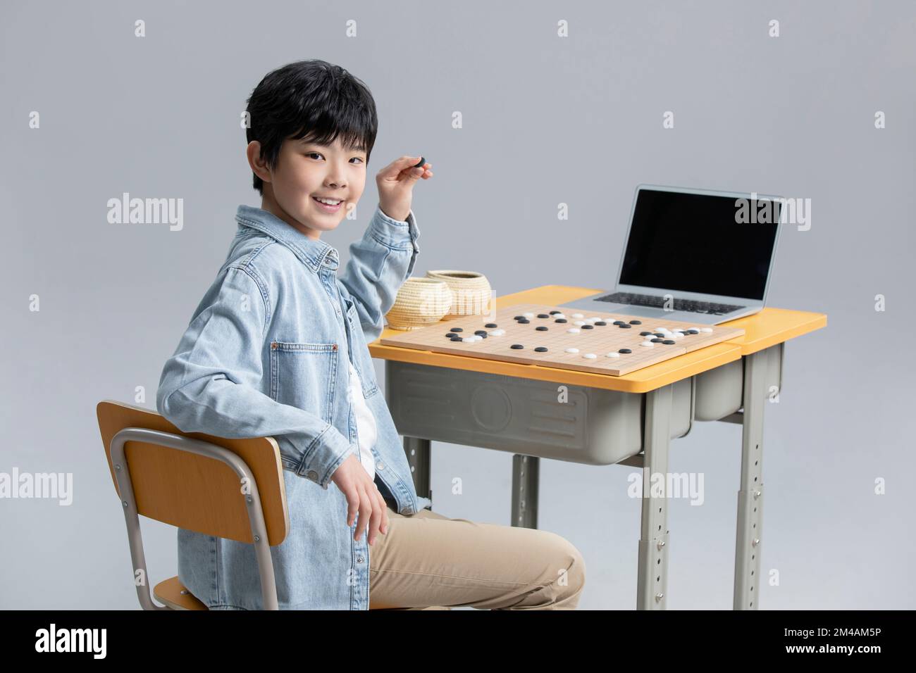 Cute Chinese boy playing the game of Go with laptop Stock Photo - Alamy