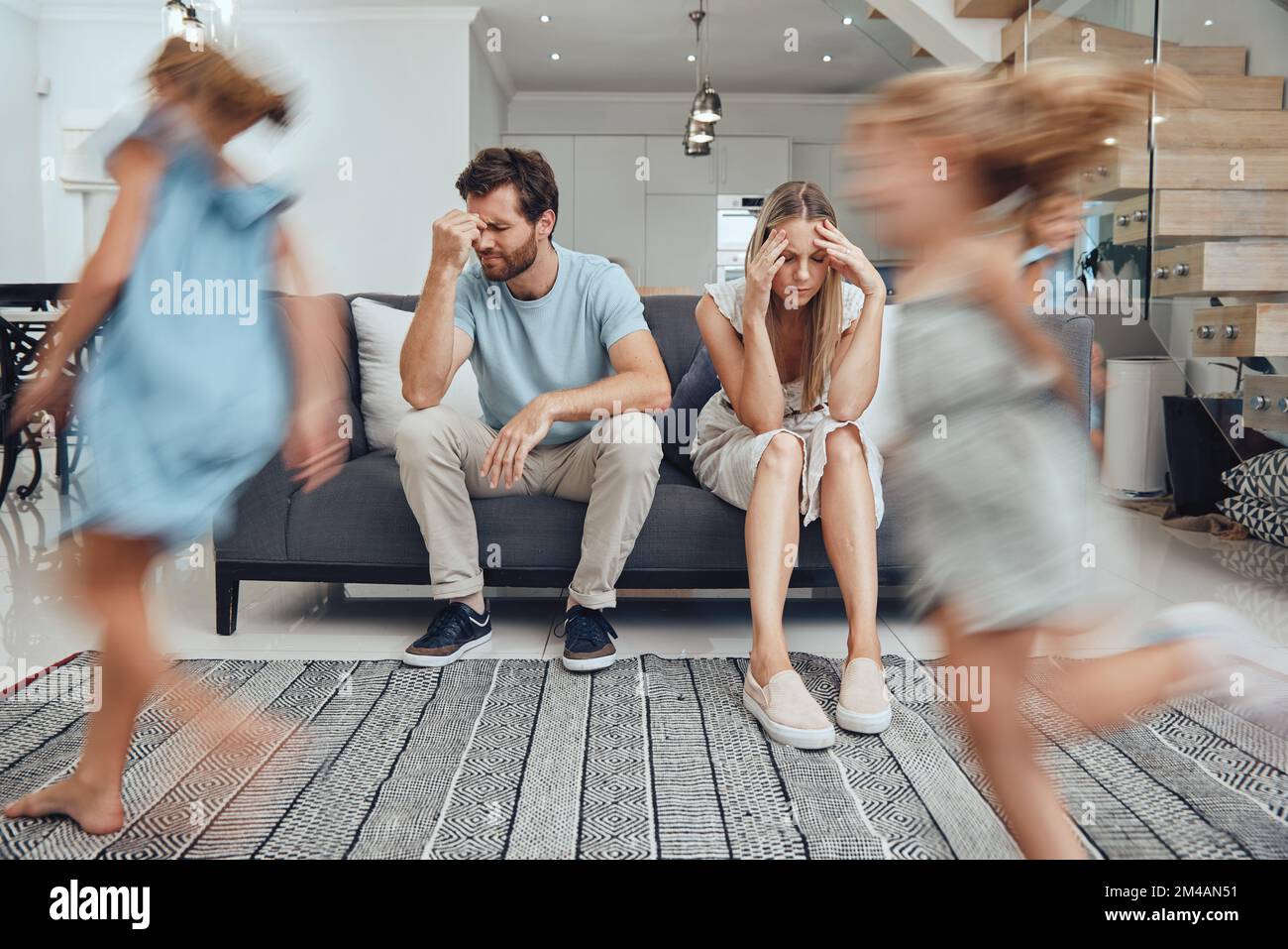 Kids running, parents on sofa tired and chaos in living room with ...