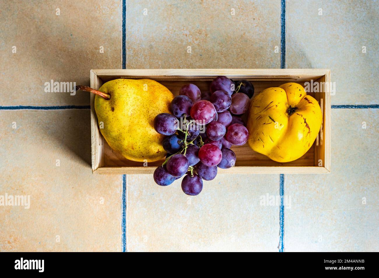 From above box with ripe organic grape, quince and pear on the concrete ...