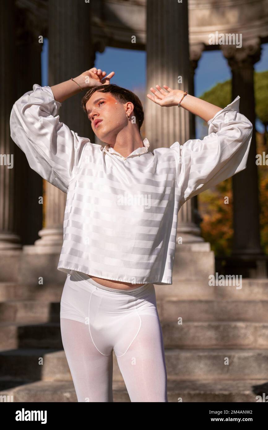Extravagant male with short hair and makeup in white shirt and ...