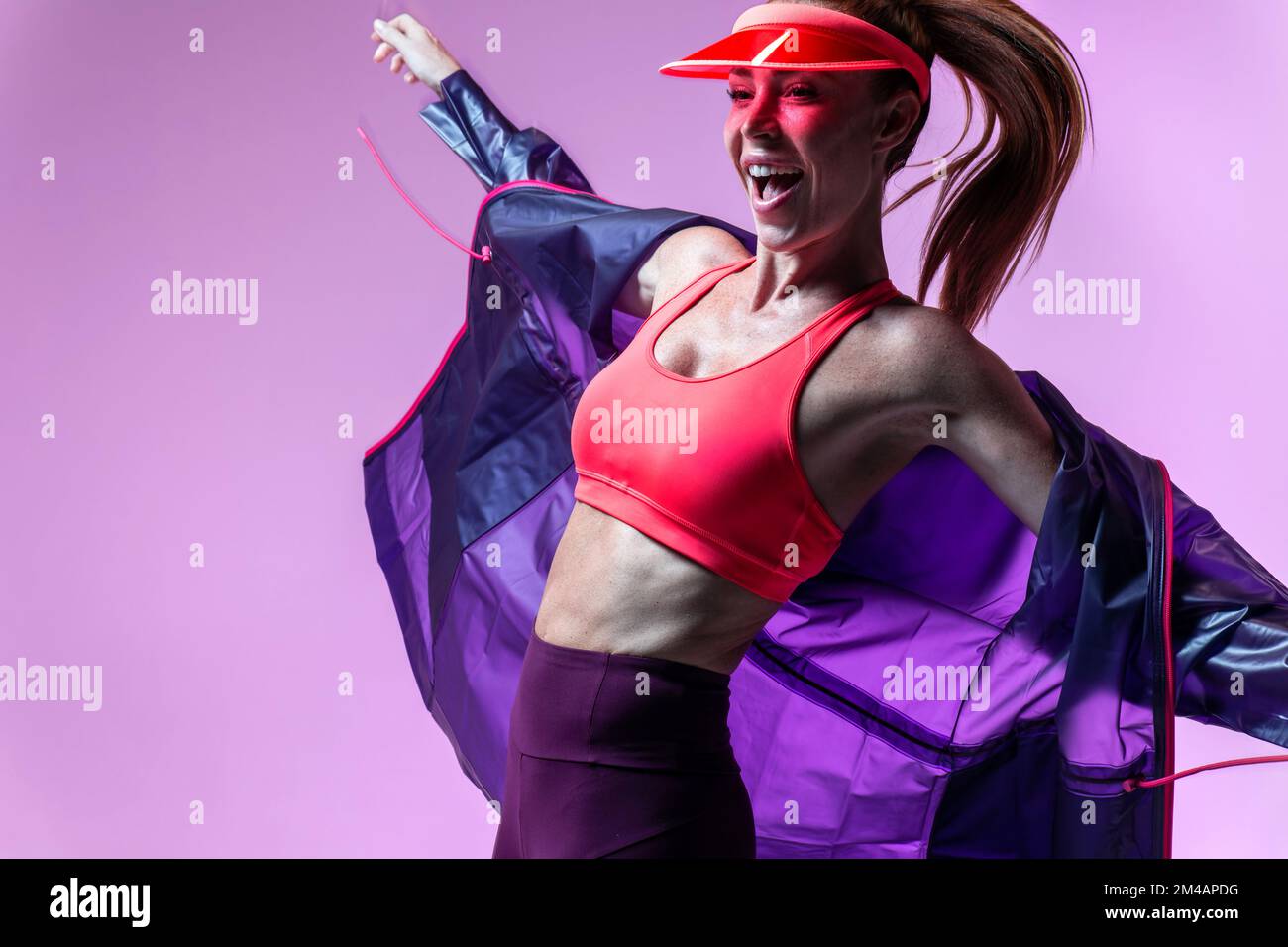Slim cheerful female athlete in stylish sportswear with raincoat and ...