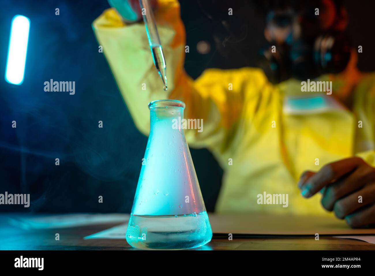Soft focus of male chemist in hazmat suit and respirator dripping ...
