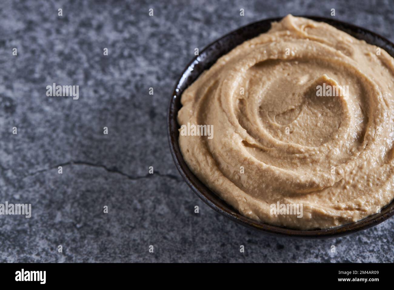 From above of fresh hummus served in bowl on cracked gray marble table ...