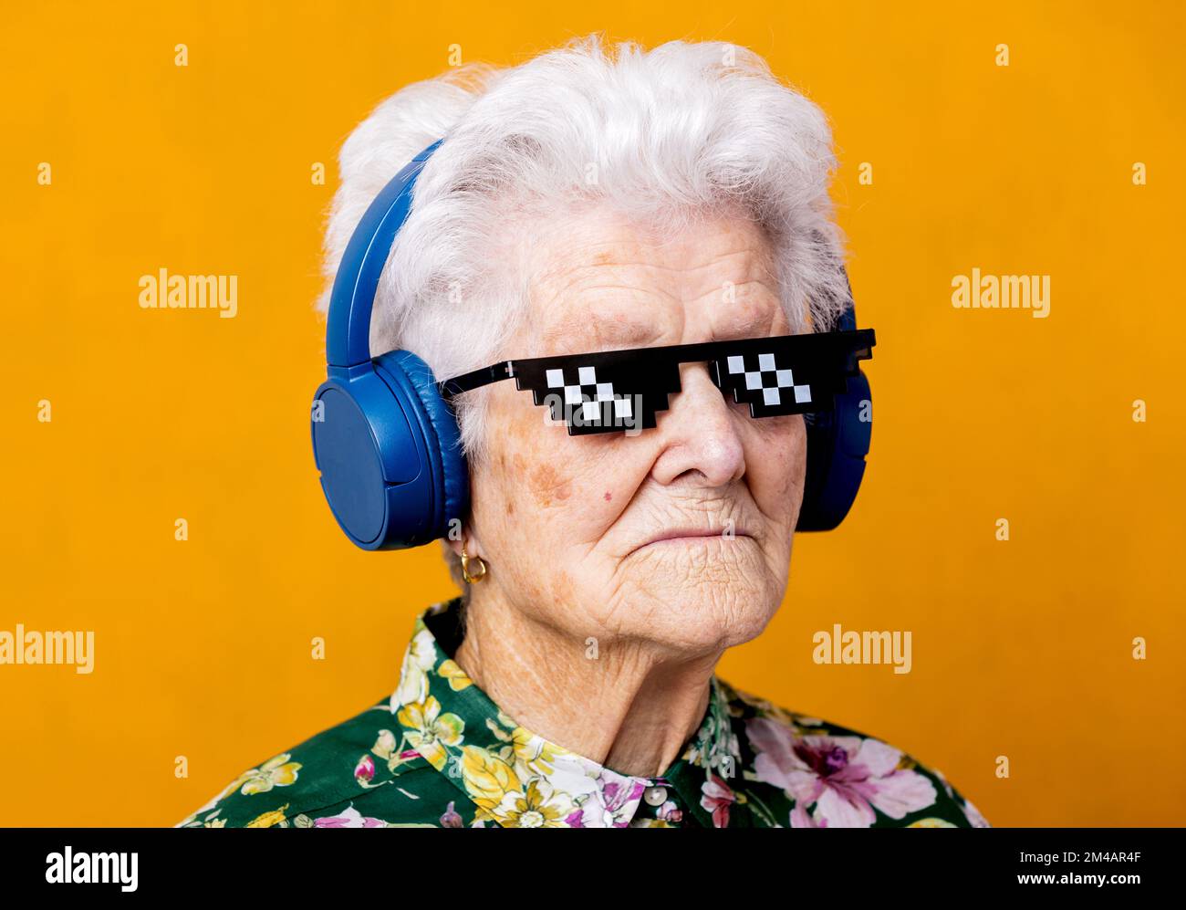 Aged female meloman in floral blouse and pixel sunglasses listening to ...