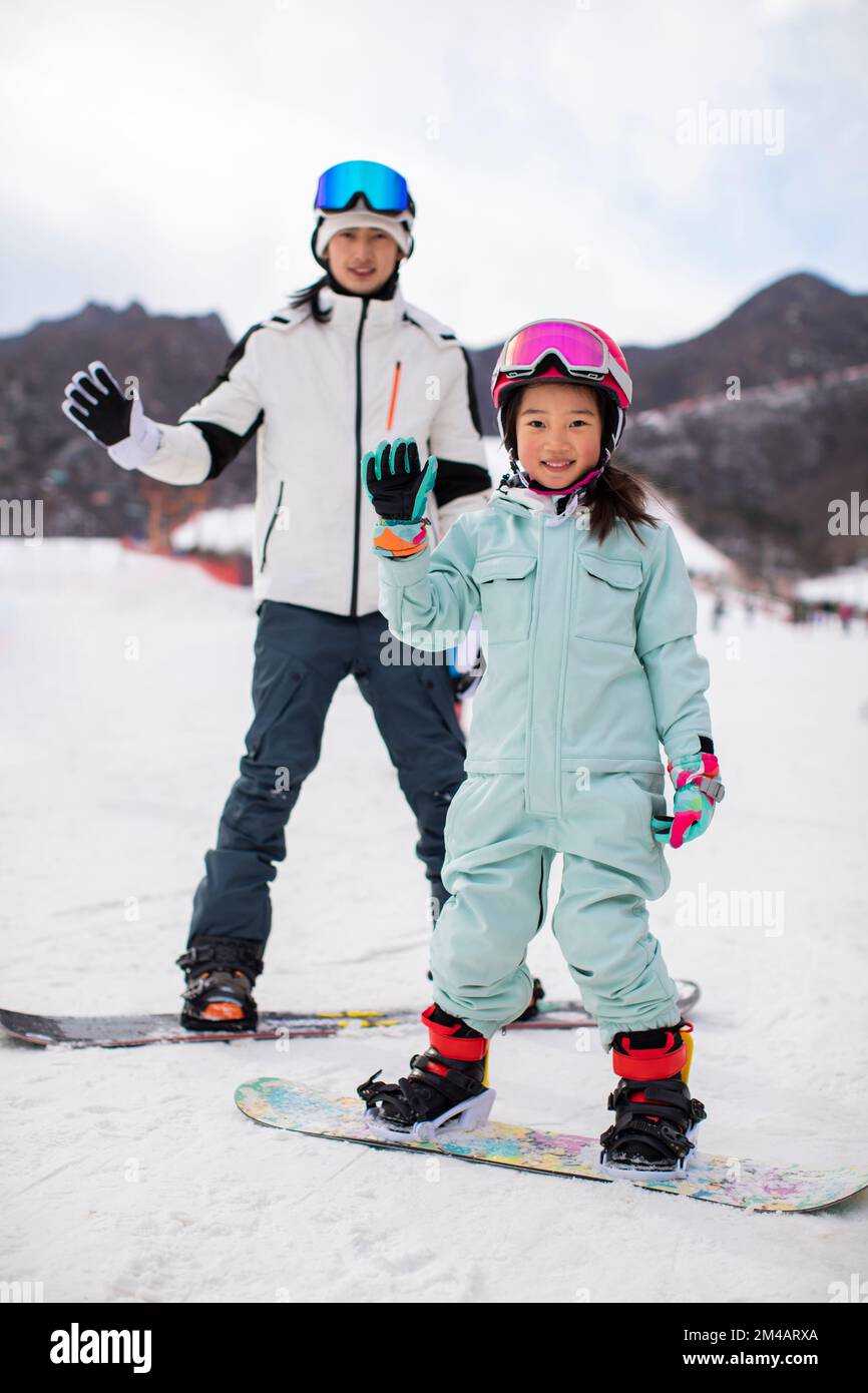 Little Chinese girl learning how to snowboard with her coach Stock ...