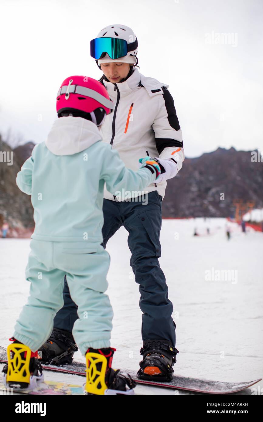 Little Chinese girl learning how to snowboard with her coach Stock Photo - Alamy