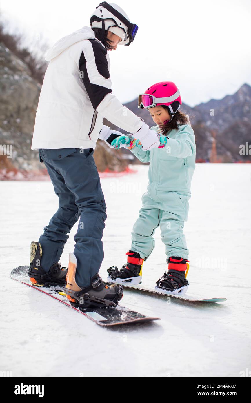 Little Chinese girl learning how to snowboard with her coach Stock Photo - Alamy