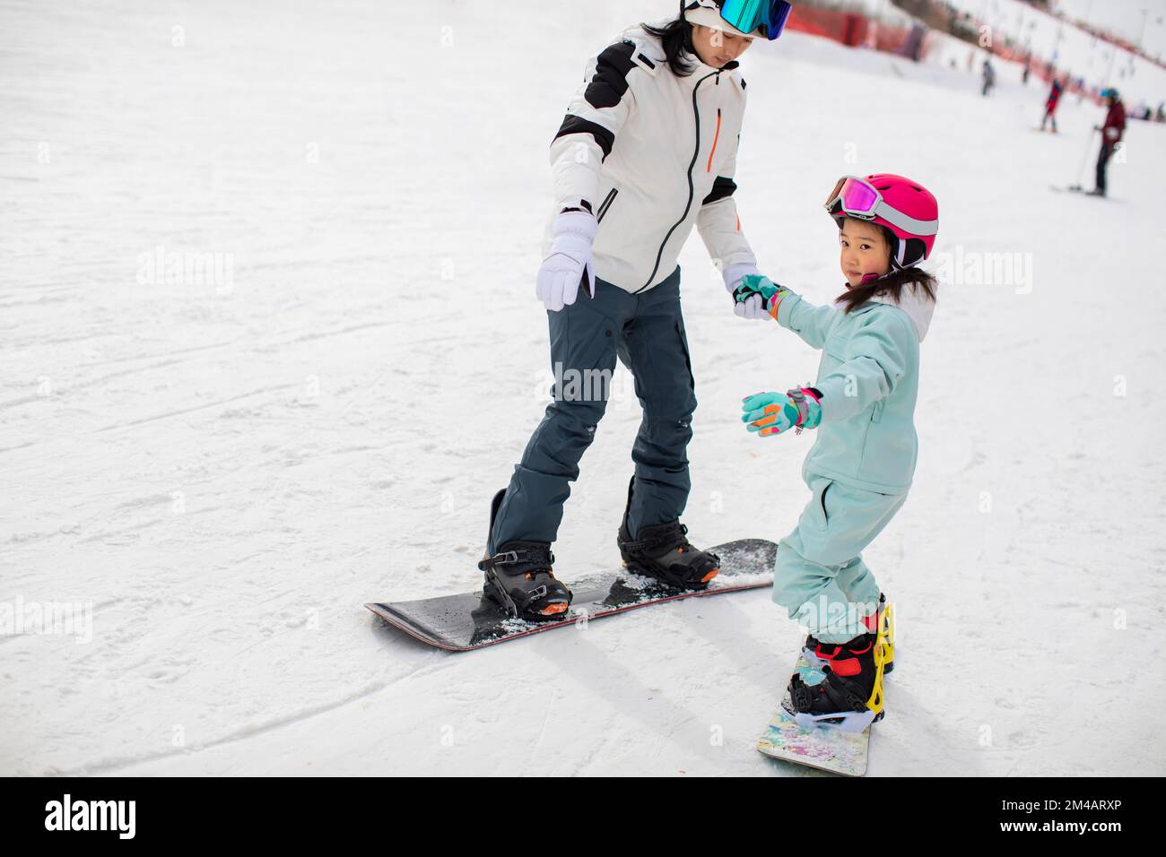 Little Chinese girl learning how to snowboard with her coach Stock ...