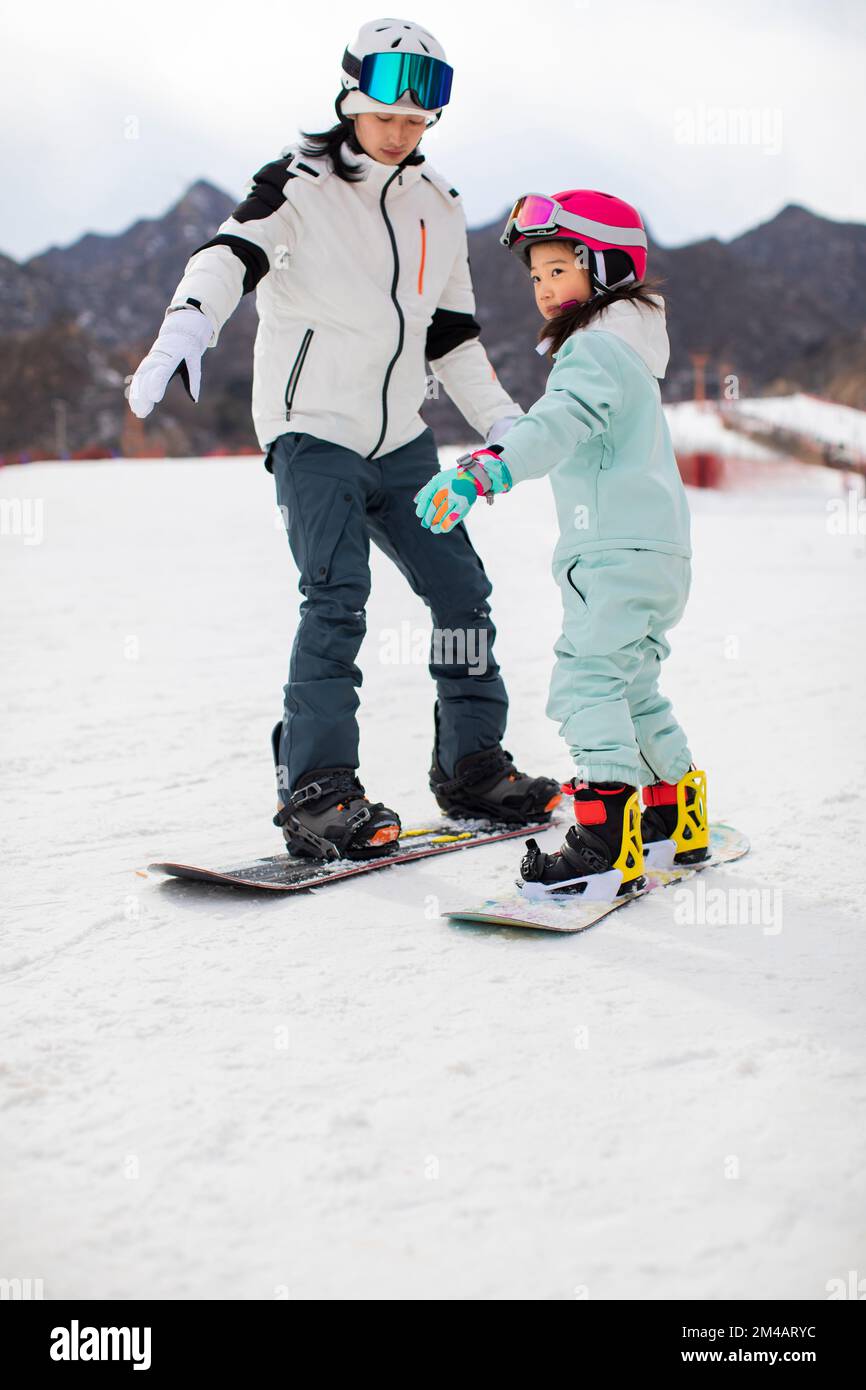 Little Chinese girl learning how to snowboard with her coach Stock ...