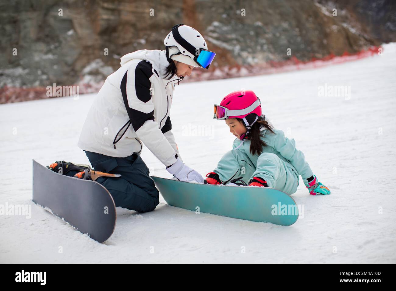 Little Chinese girl learning how to snowboard with her coach Stock Photo - Alamy