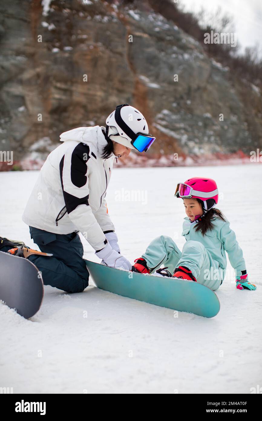 Little Chinese girl learning how to snowboard with her coach Stock ...
