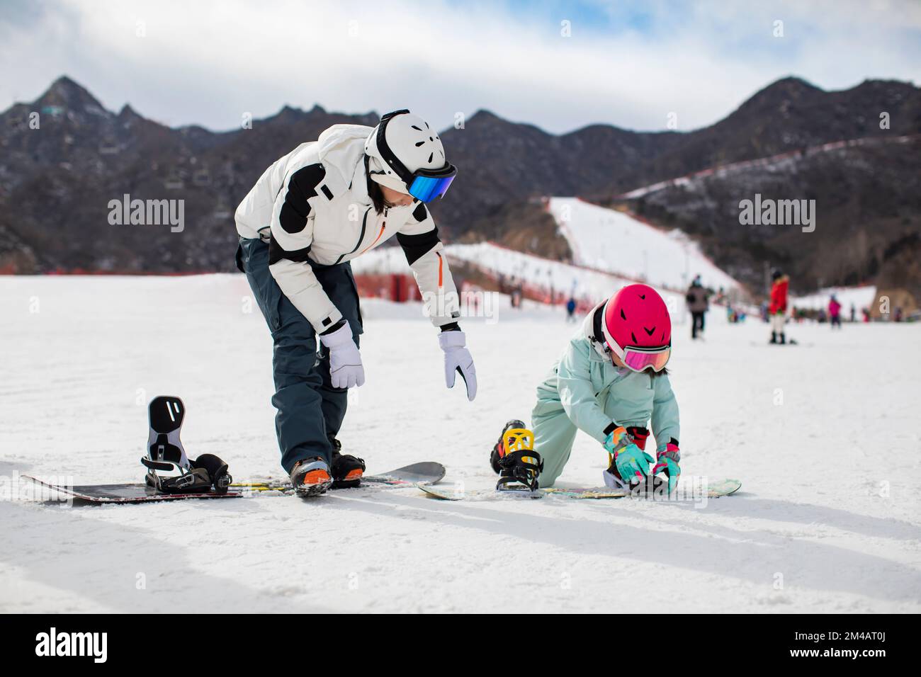 Little Chinese girl learning how to snowboard with her coach Stock ...