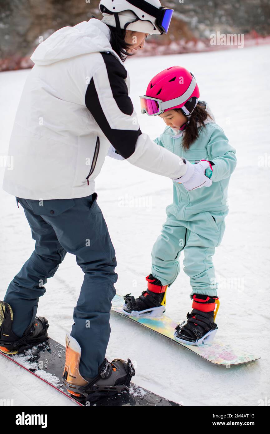 Little Chinese girl learning how to snowboard with her coach Stock ...