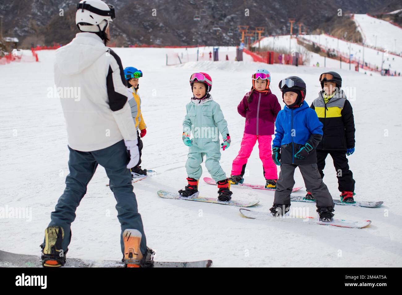 Chinese children learning how to snowboard with their coach Stock Photo ...