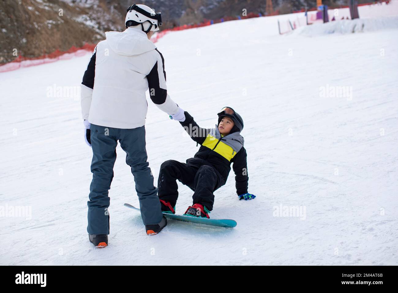 Little Chinese boy learning how to snowboard with his coach Stock Photo ...