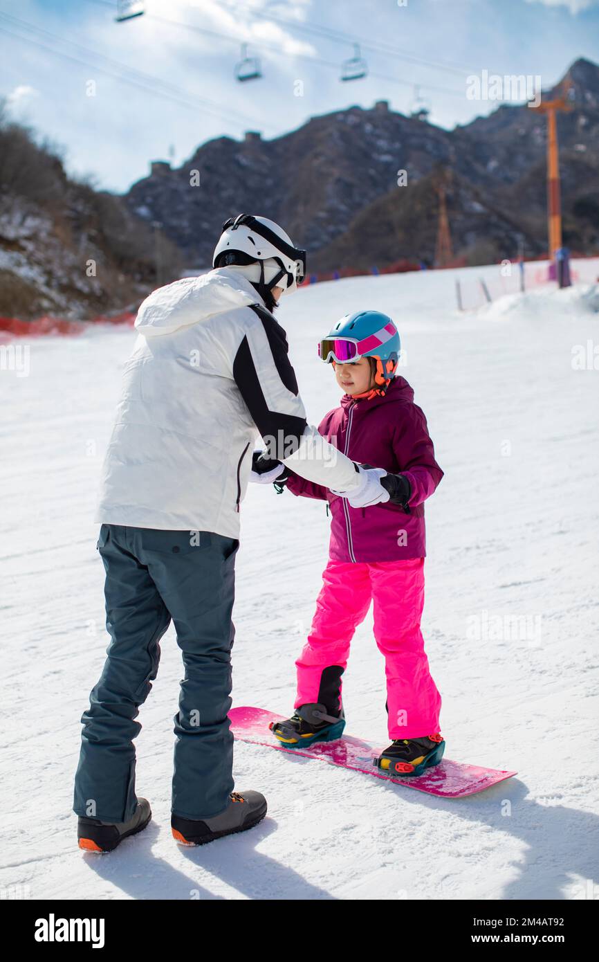 Little Chinese girl learning how to snowboard with her coach Stock ...