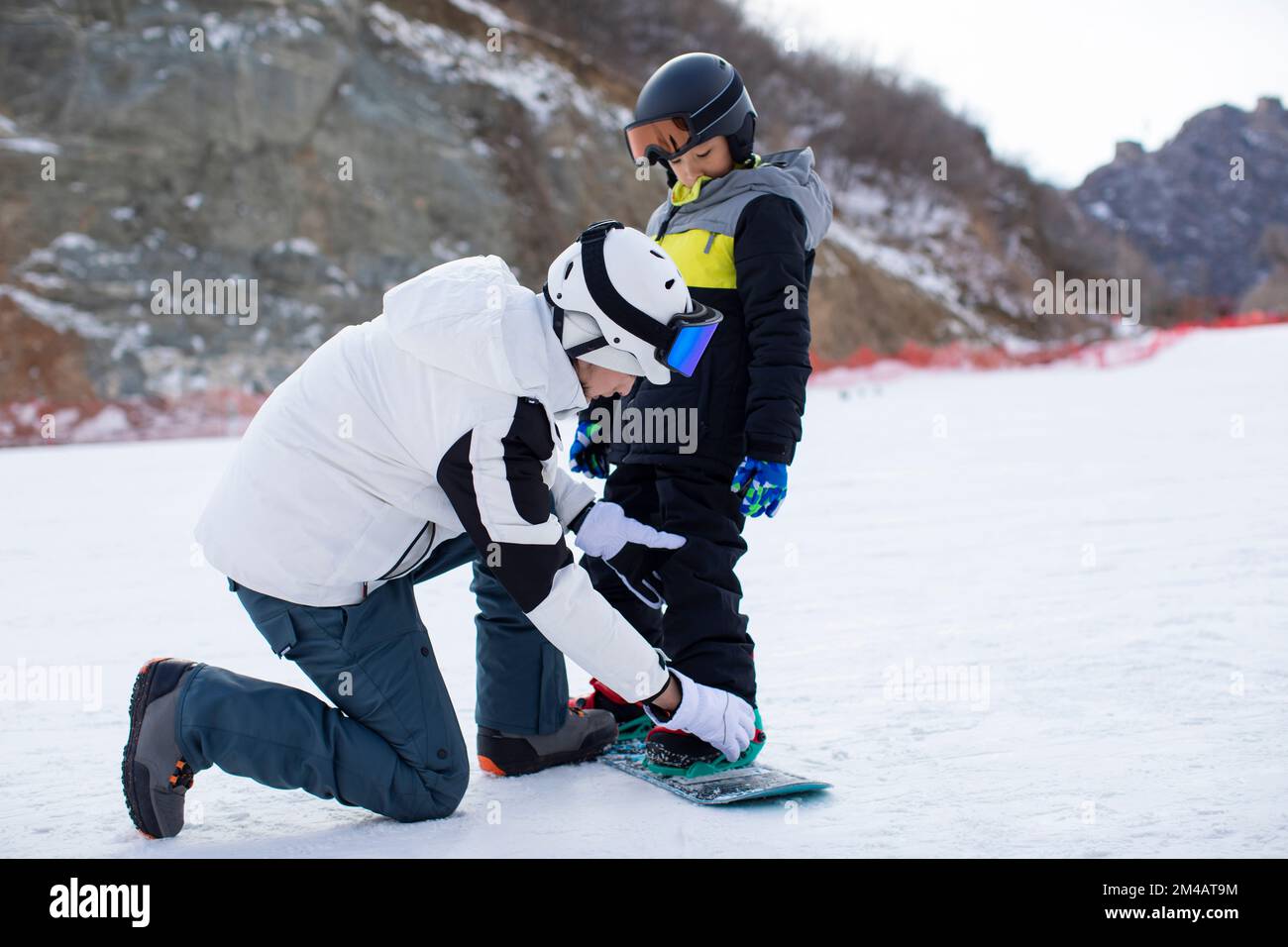 Little Chinese boy learning how to snowboard with his coach Stock Photo ...