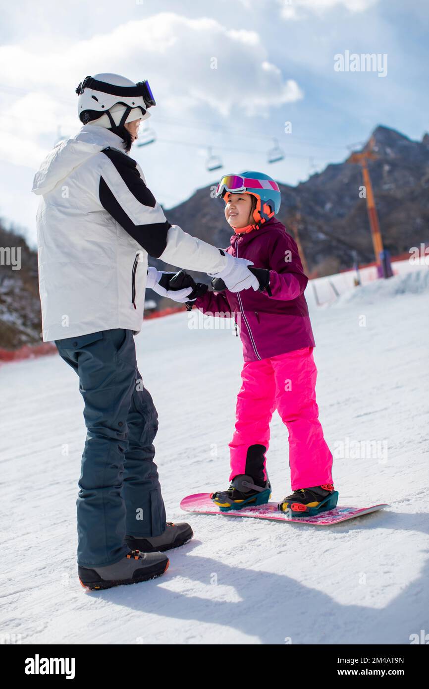Little Chinese girl learning how to snowboard with her coach Stock ...