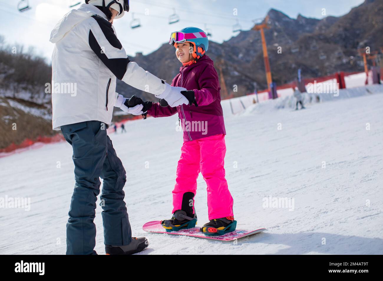 Little Chinese girl learning how to snowboard with her coach Stock ...