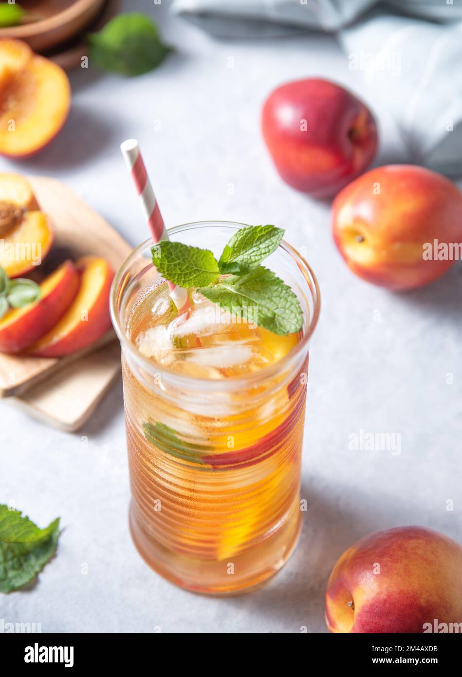 cool peach tea with mint and ice in a glass on a blue background. Top ...