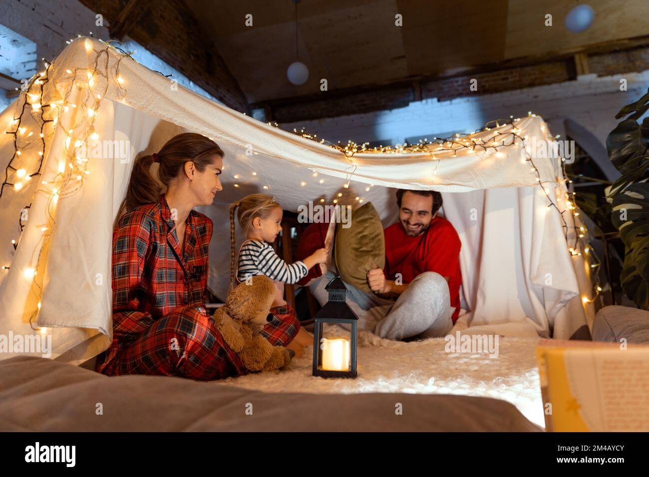 Happy family, mother, father and daughter playing inside hut with ...