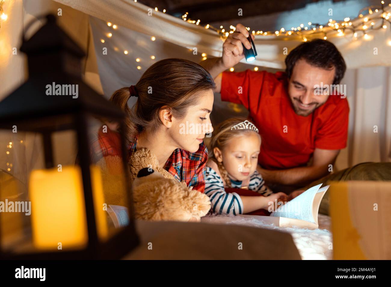 Happy family, mother, father and daughter lying inside hut, tent in ...
