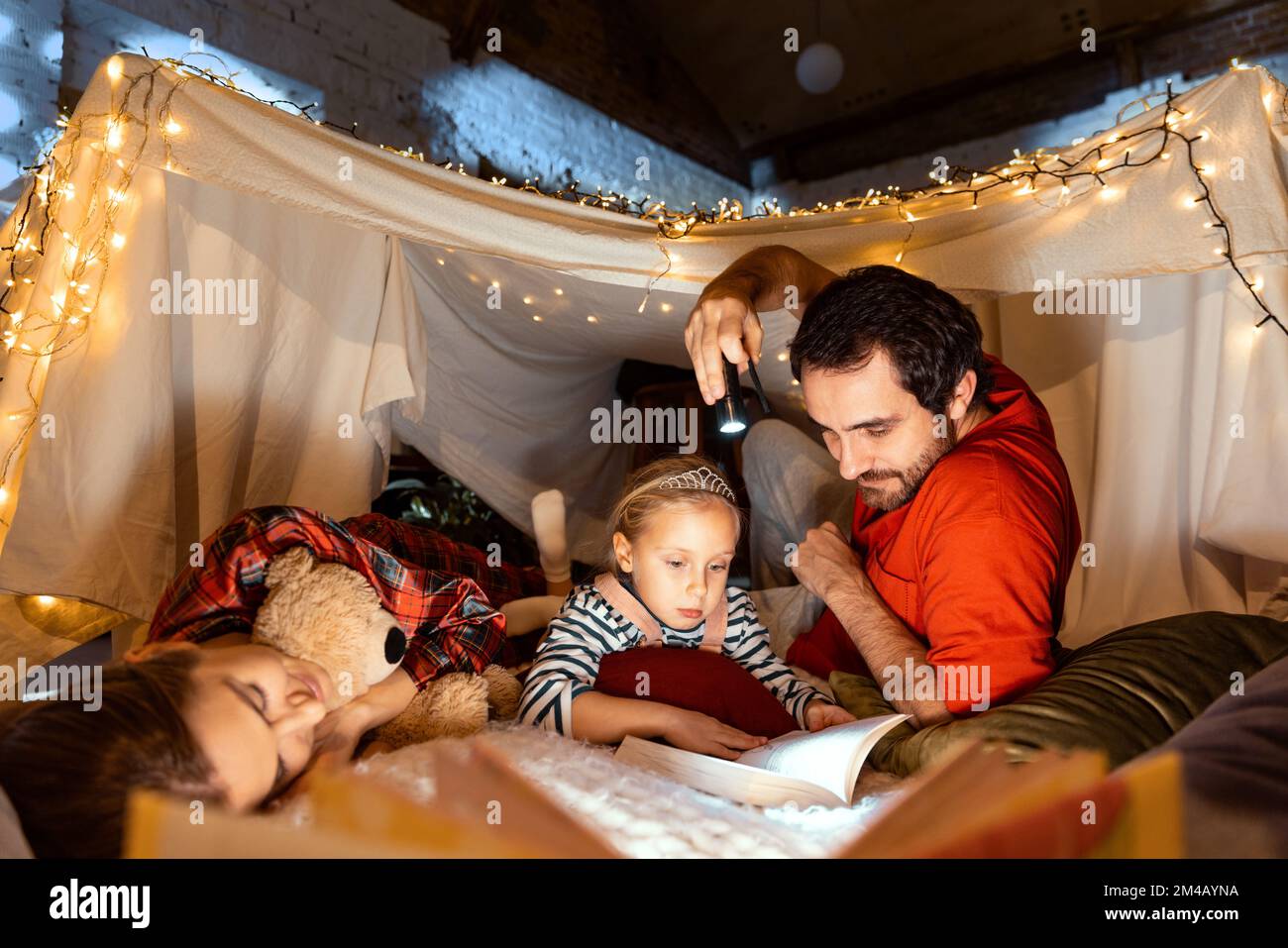 Happy mother, father and daughter lying inside self-made hut, tent in ...