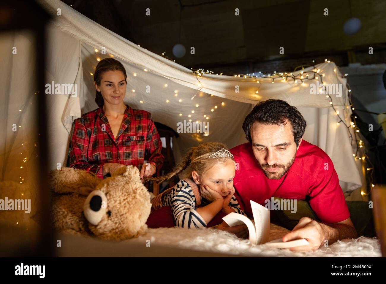 Loving family. Mother, father and daughter lying inside self-made hut ...