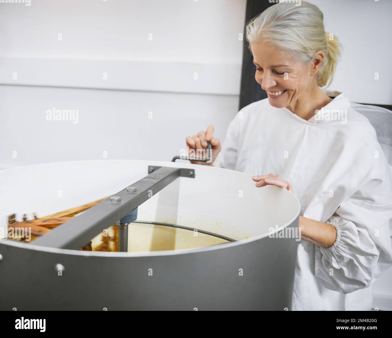 Woman, beekeeper and machine for honey production at factory. Agro ...