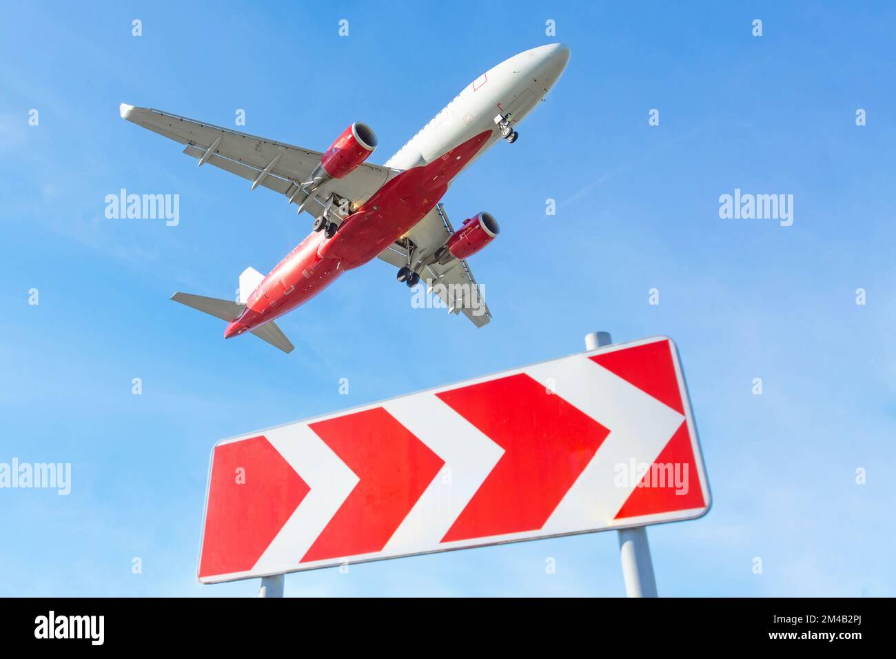 Airplane flying in the sky, landing over a sign with striped red and ...