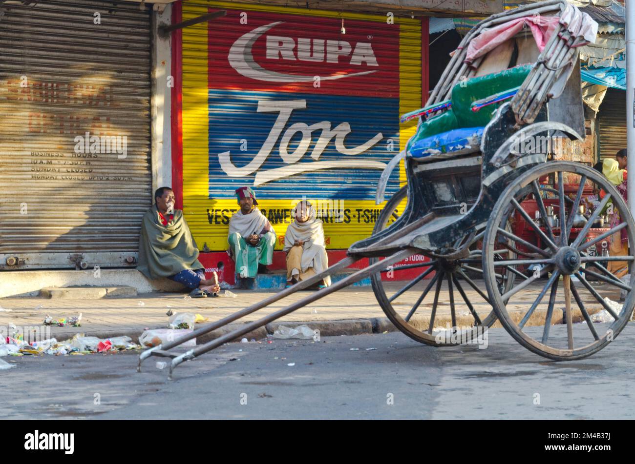 Three people sitting in front of a colorful commercial, pull rikshaw ...