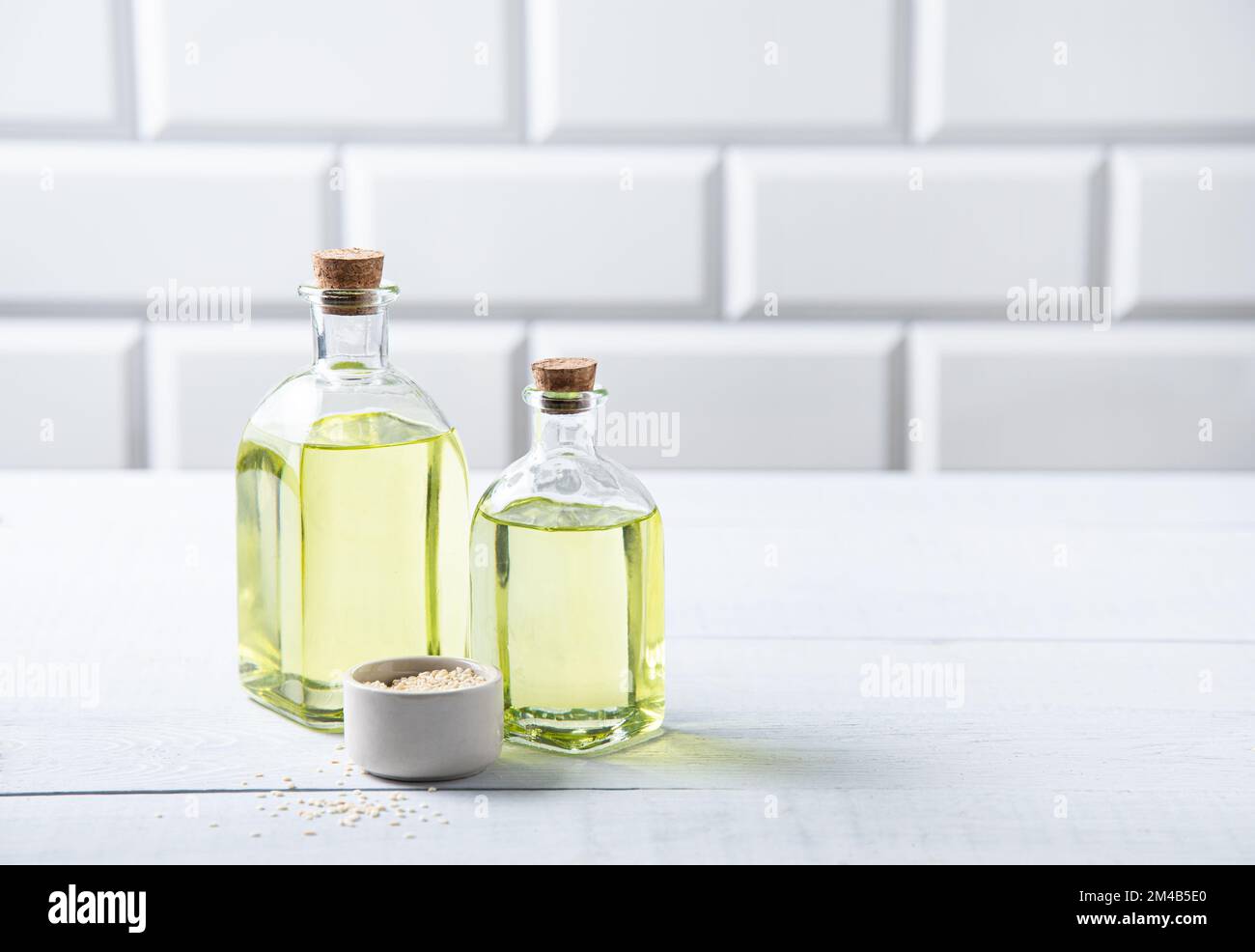 Natural vegetable oil from sesame seeds in a clear bottle on the white ...