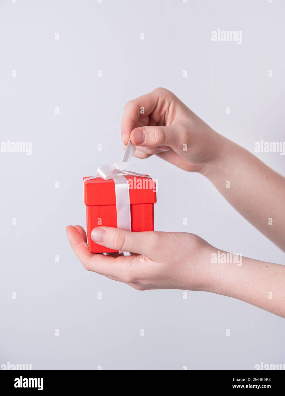 Women's hands open red holiday gift box with white ribbon. Front view ...